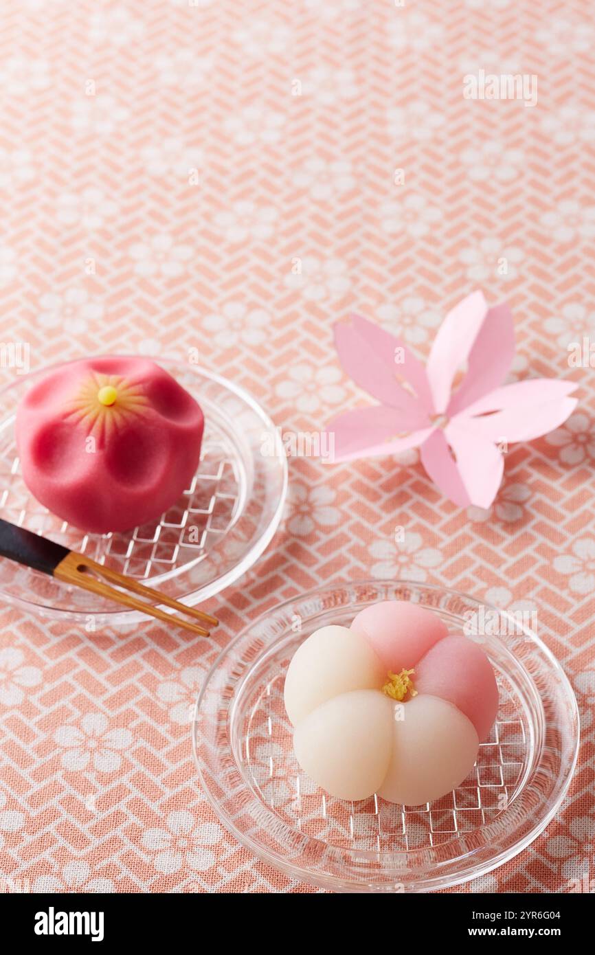 Ume paste sweets and paper cherry blossoms placed on a ume-patterned ...