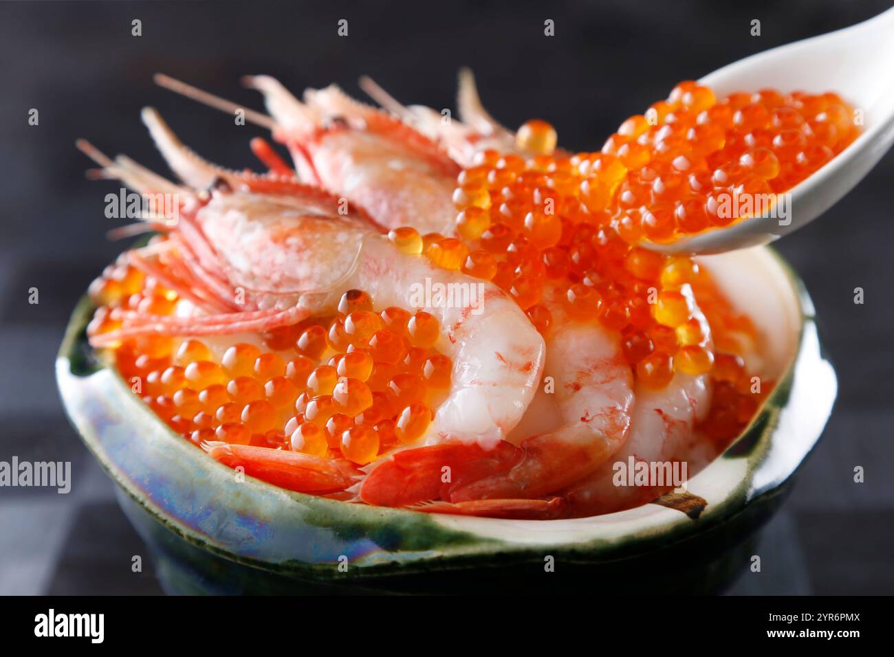 Photo of the process of pouring salmon roe over Botan prawns Stock ...