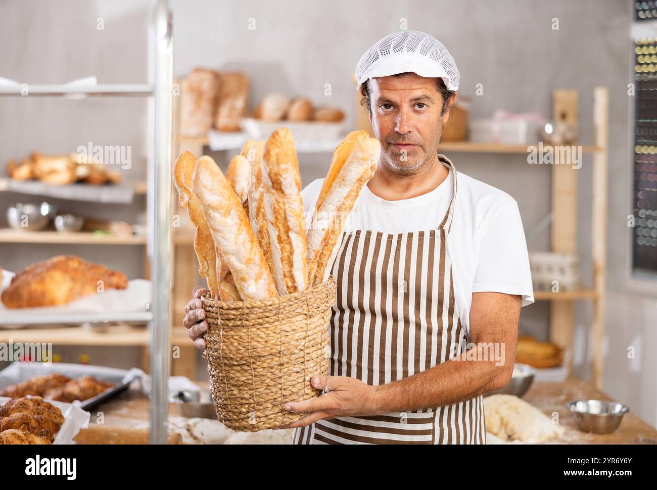 Smiling male salesman showing assortment of bakery products behind ...