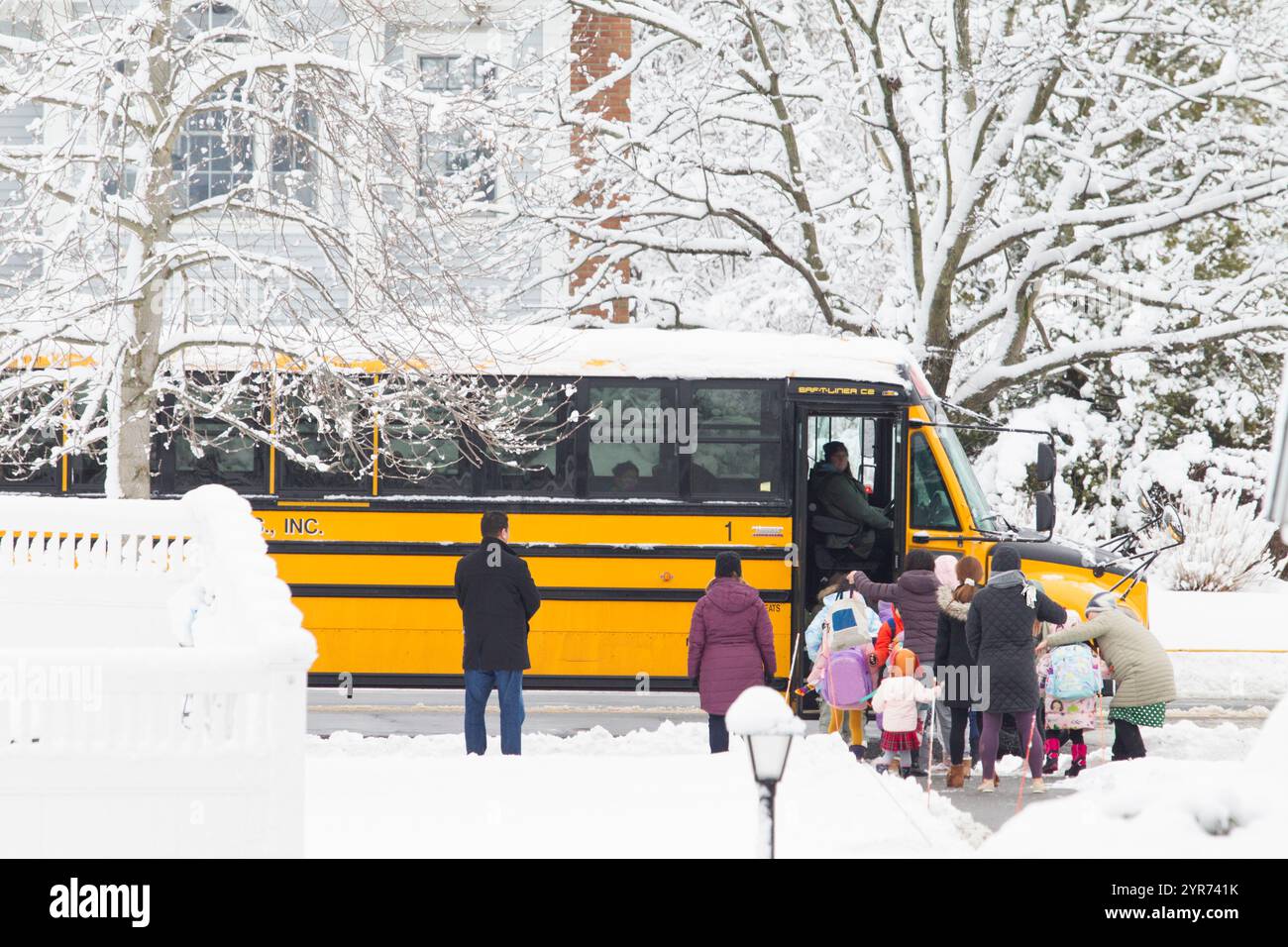 Children and parents are waiting for the school bus on a snow day in ...