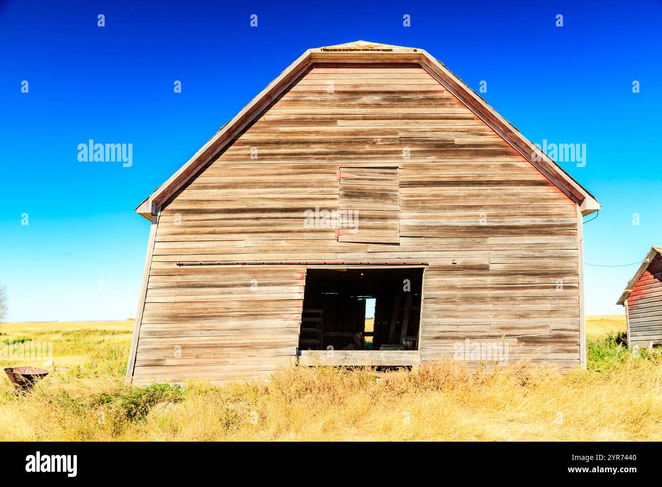 A large, old barn with a window in the middle of the wall. The barn is ...