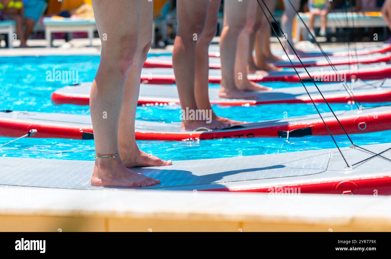People balancing on paddleboards in a tropical pool before a yoga ...