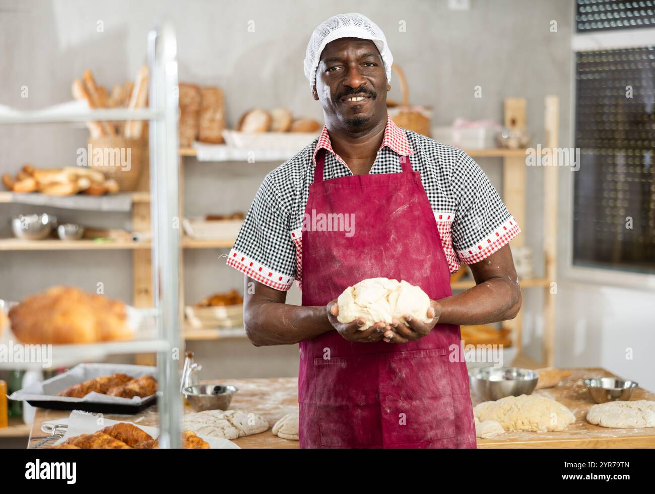 Smiling African baker standing with dough in cozy bakery Stock Photo ...
