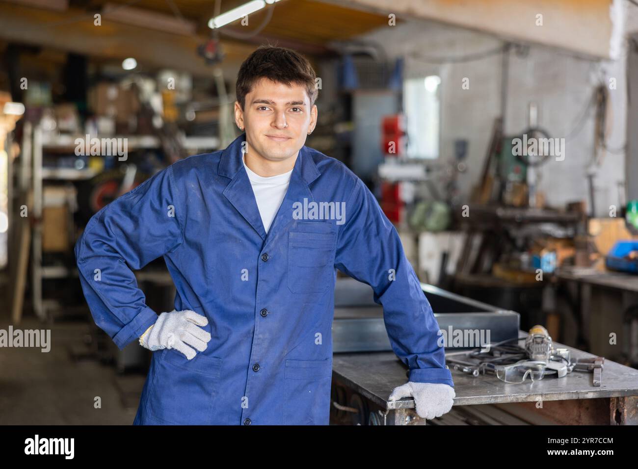 Portrait of young mechanic in the interior of a production shop of ...