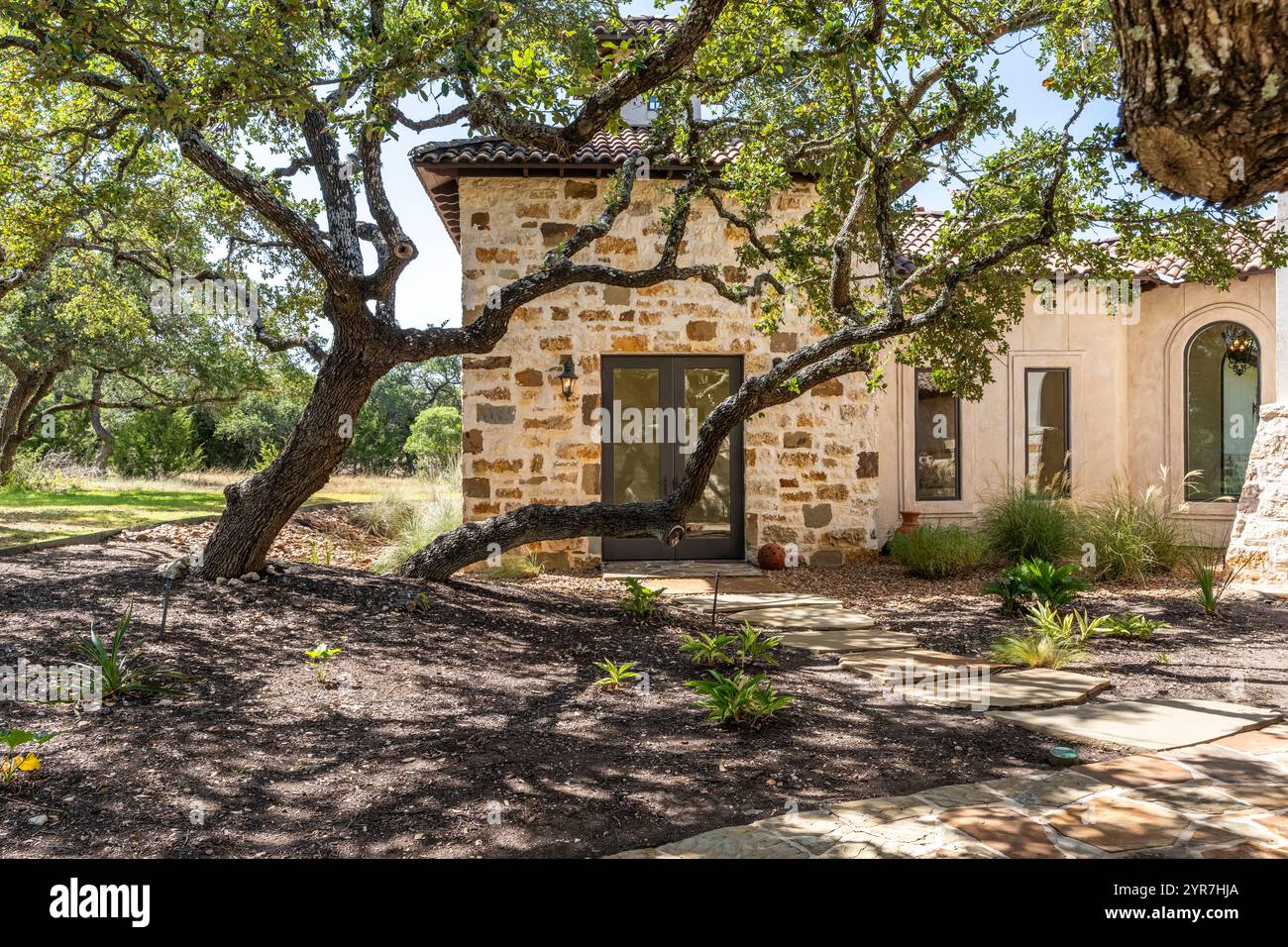 Rustic stone house surrounded by mature trees and lush landscape in ...