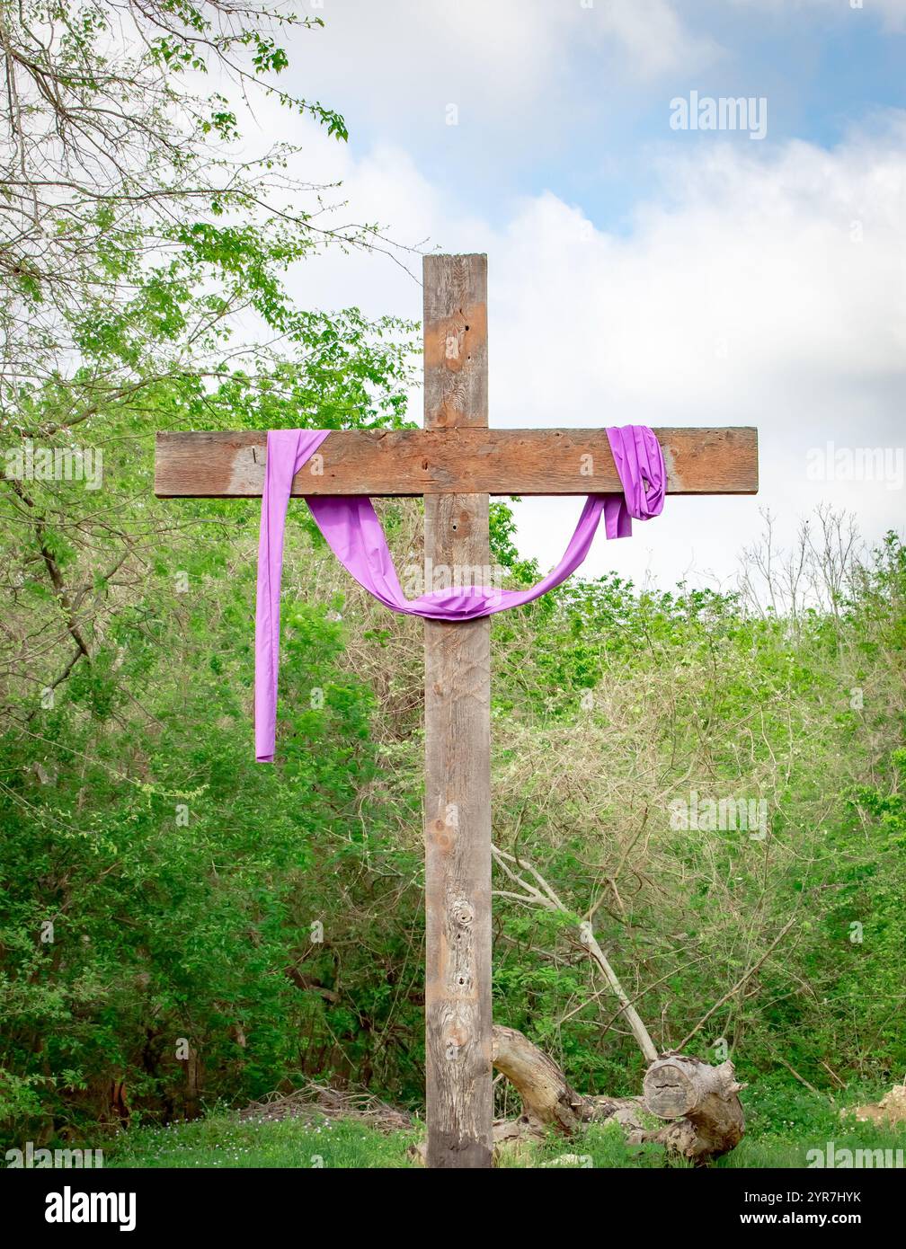 Wood Cross with a purple satin cloth draped on it. Background is green ...