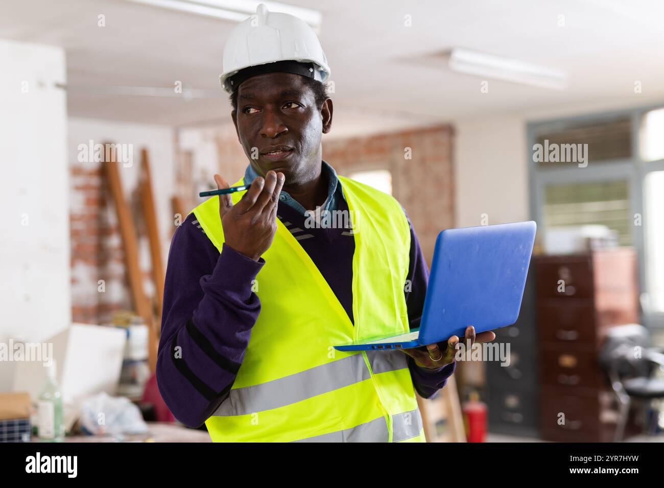 Man construction worker with laptop talking ob phone inside apartment ...