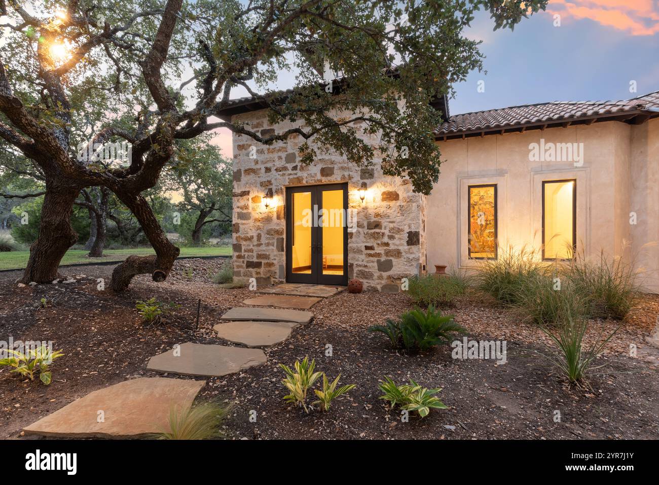 Rustic stone house surrounded by lush greenery at sunset Stock Photo ...