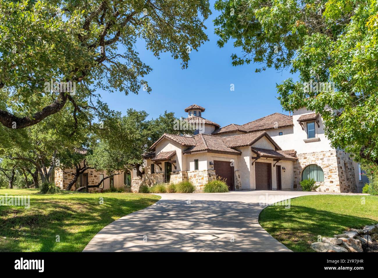Beautiful hillside home surrounded by lush trees and clear blue skies ...