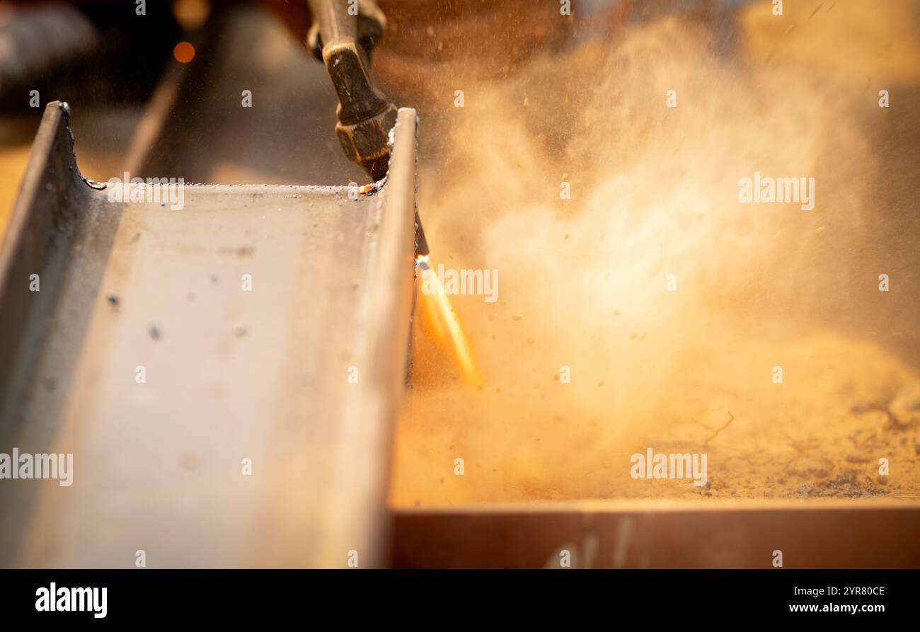 A man working with a torch cutting metal. Hazards of industrial work ...