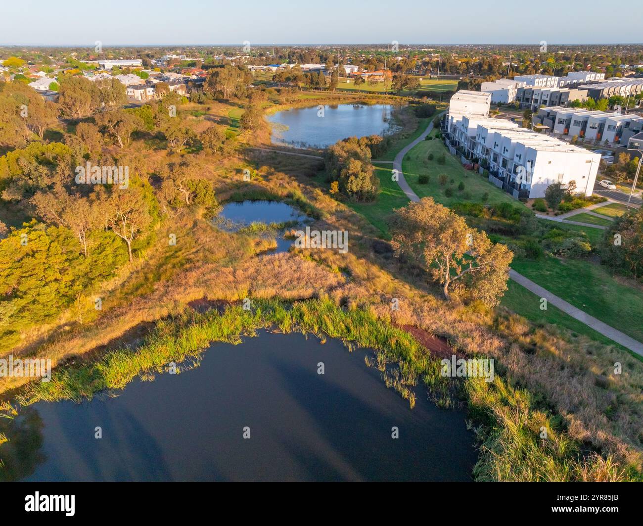 Aerial view of a row of apartments alongside a suburban wetland with ...