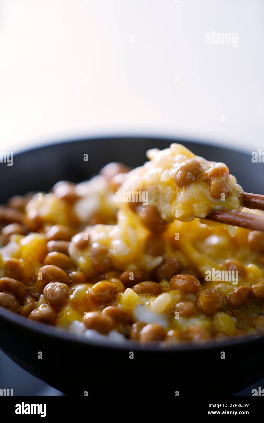 Natto and egg rice with natto and egg yolk lifted up with chopsticks ...