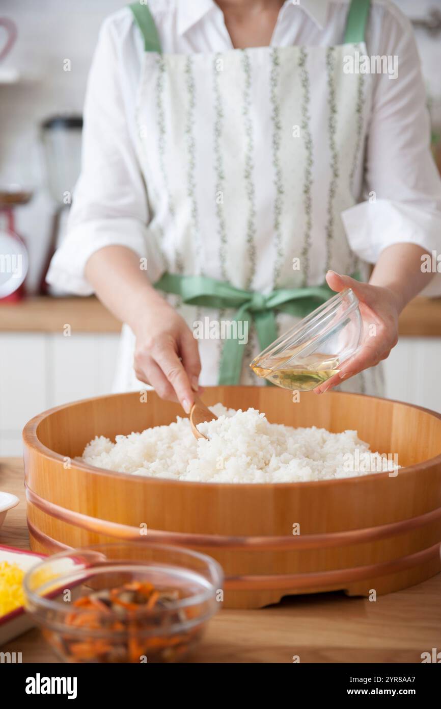 Woman pouring vinegar over rice to make sushi rice Stock Photo - Alamy