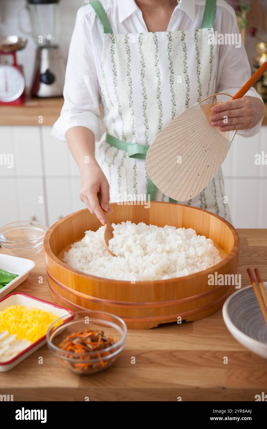 Woman making sushi rice by cooling rice mixed with vinegar Stock Photo ...