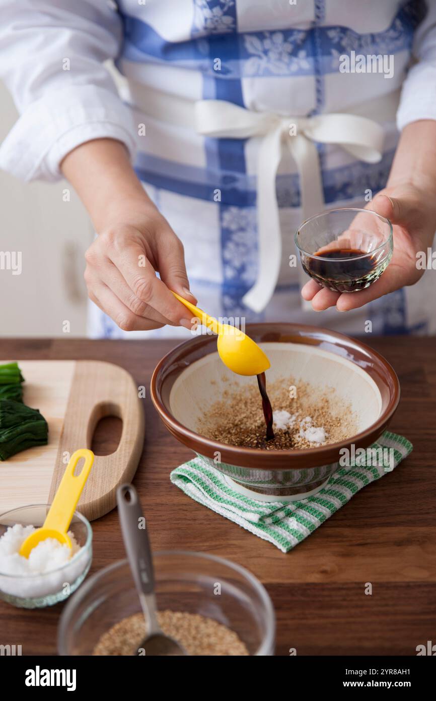 Woman adding seasoning to ground sesame seeds Stock Photo - Alamy
