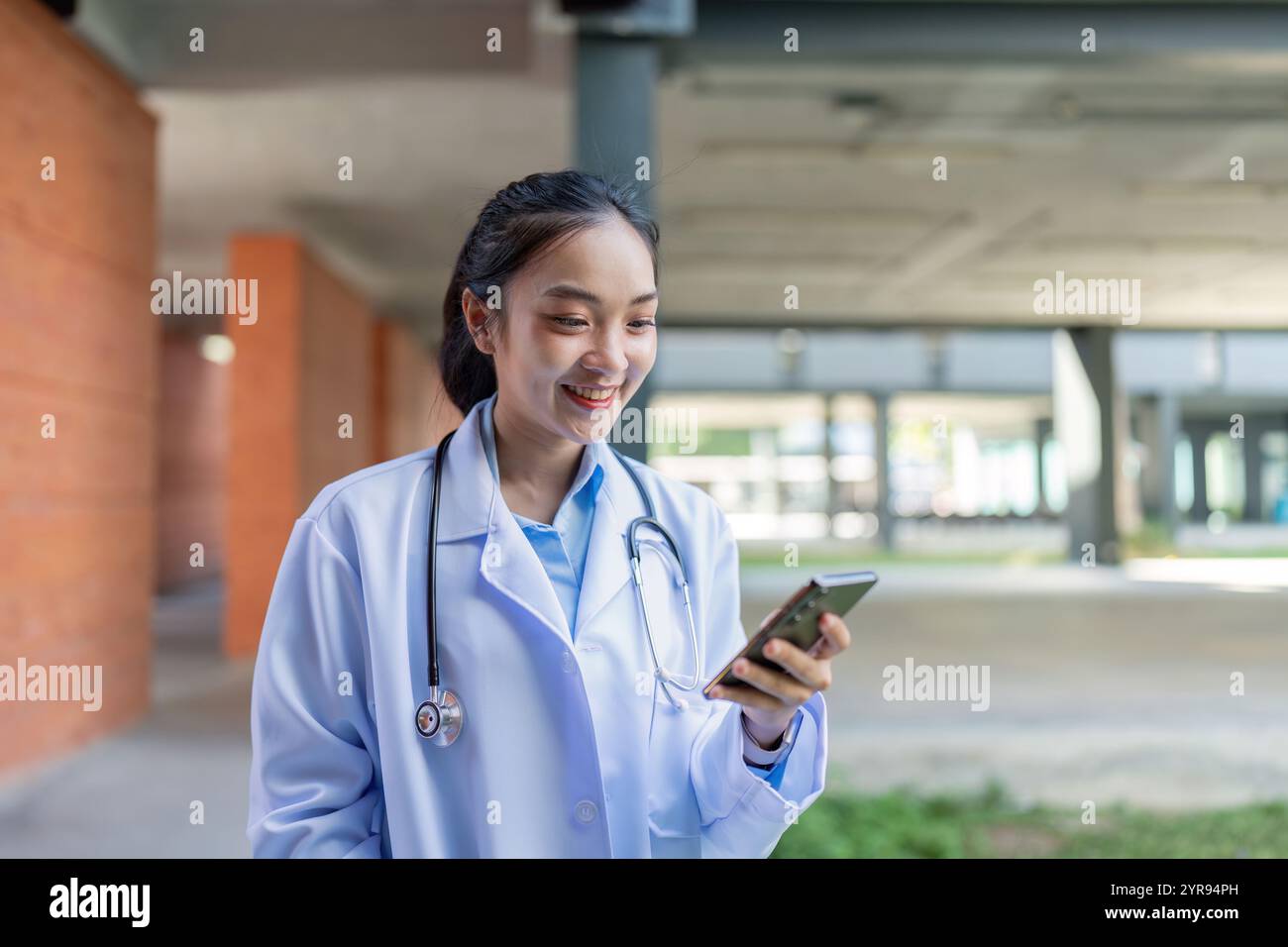 Asian female doctor using a smartphone outdoors Stock Photo - Alamy