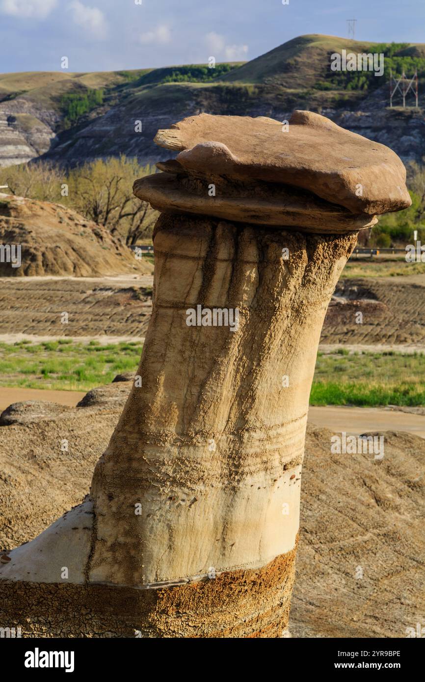 A large rock formation with a small cap on top. The rock is brown and ...
