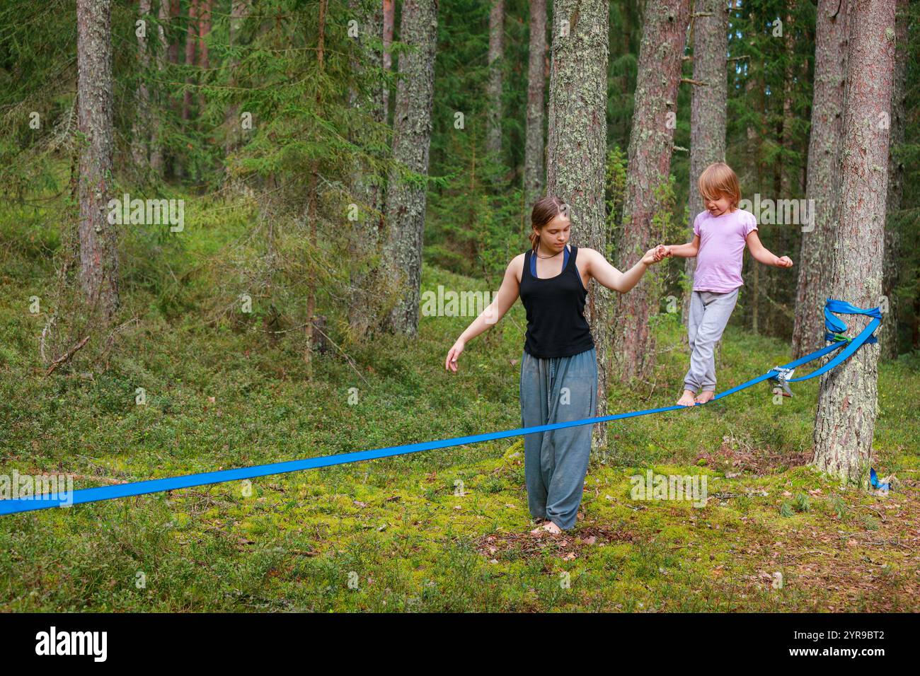 A teenage girl assists a young girld as she carefully balances on a ...
