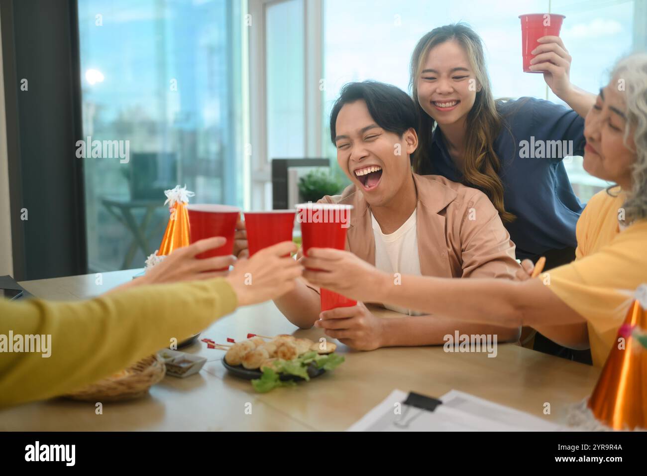 Group of colleagues laughing and clinking cups to celebrate at office ...