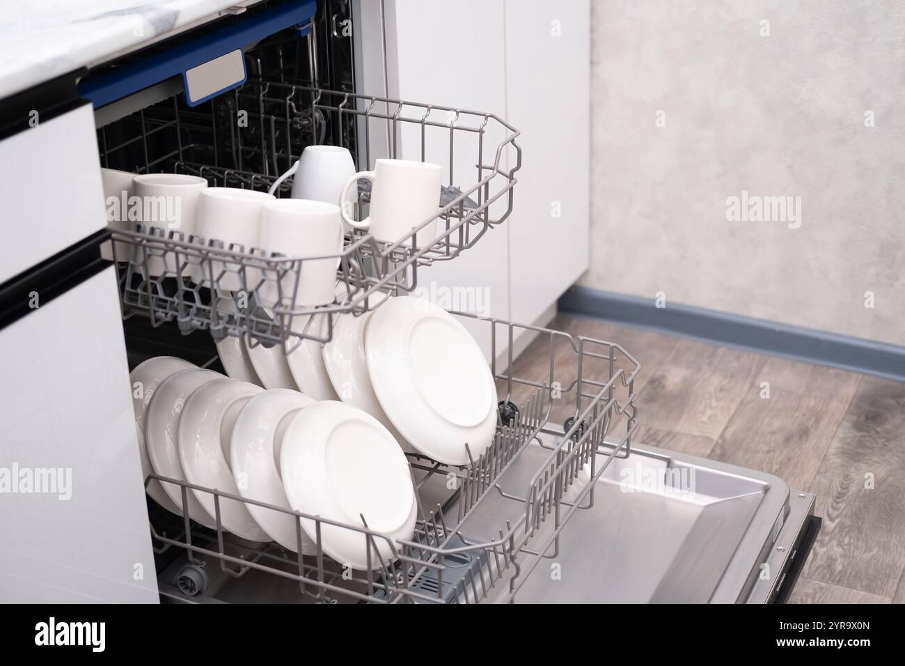 Built-in dishwasher door open. Kitchen with built-in appliances. Plates ...