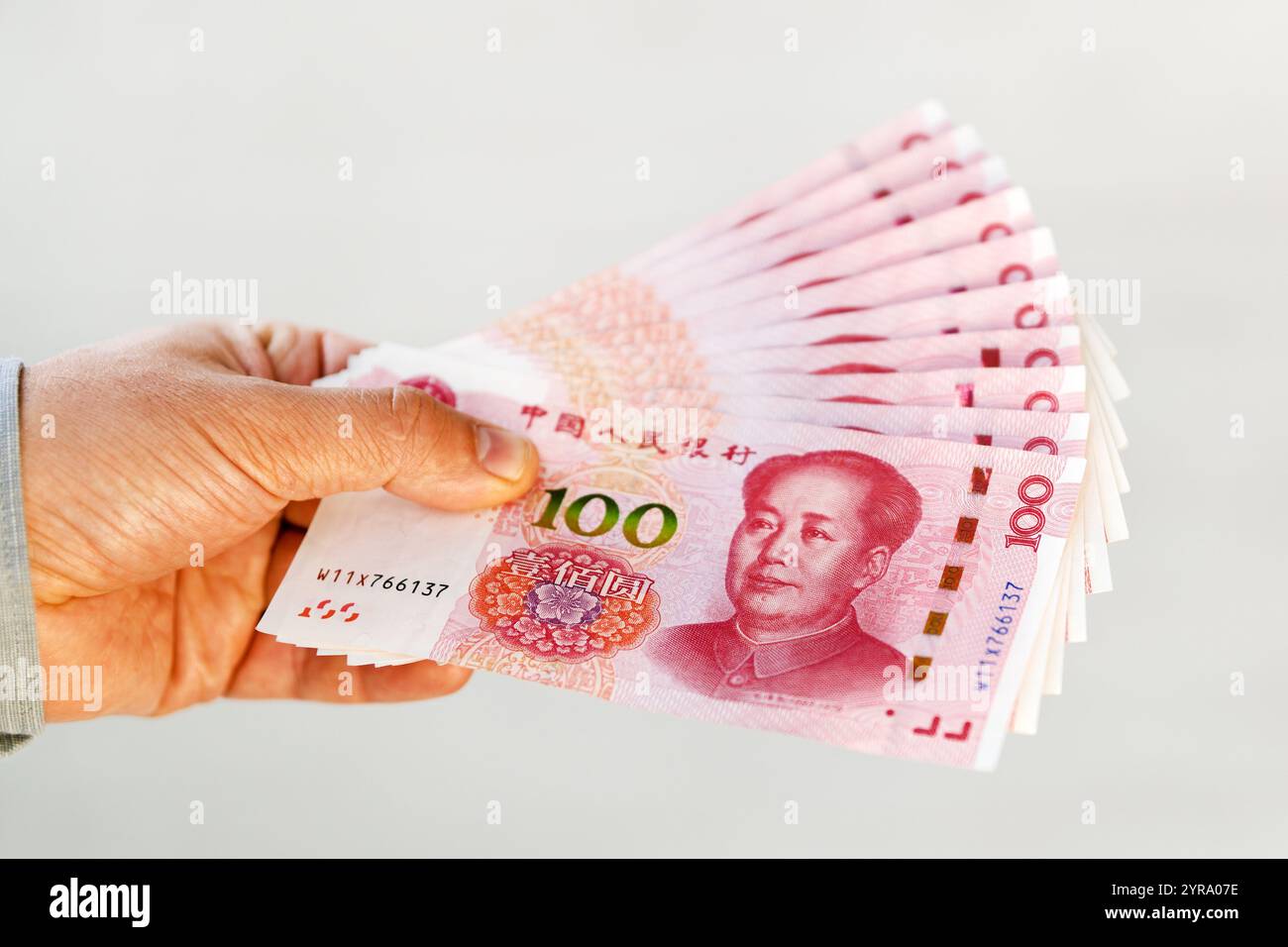 Hand Holding Stack of 100 Yuan Notes. Translate alphabet Yibai yuan ...