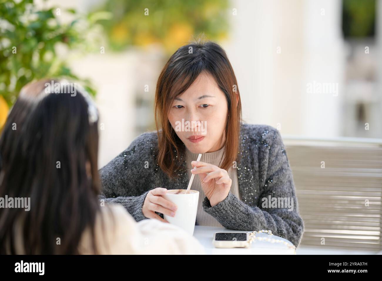 A Singaporean woman in her 40s is drinking hot chocolate while talking ...