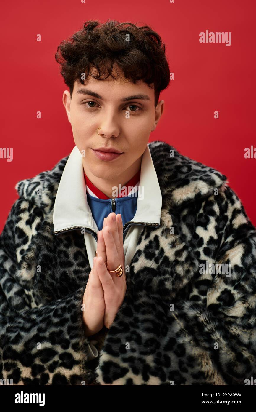 Stylish person in a striking coat poses meditatively with hands ...