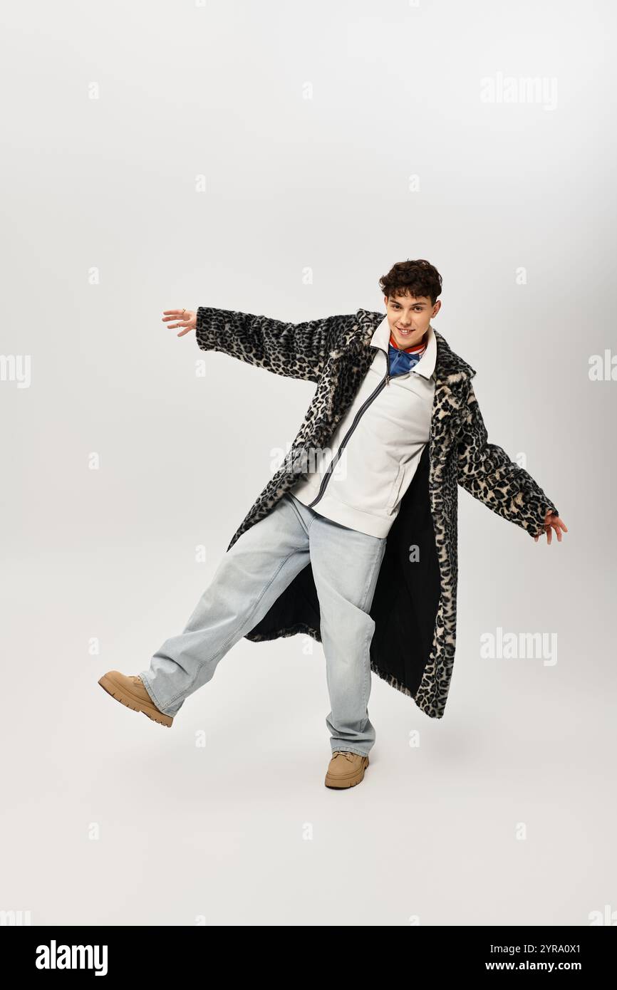 Stylishly dressed man in oversized coat poses playfully under studio ...