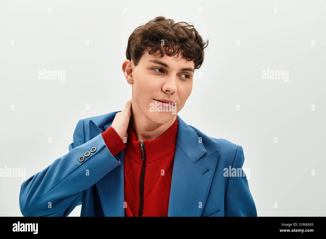 Stylish young man showcases a modern look, playfully adjusting his ...