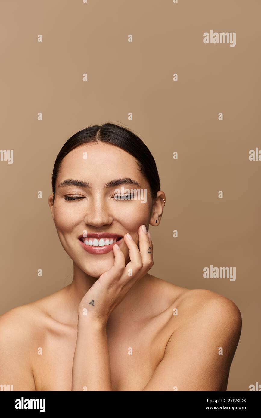 A young woman smiles brightly with closed eyes, radiating happiness ...