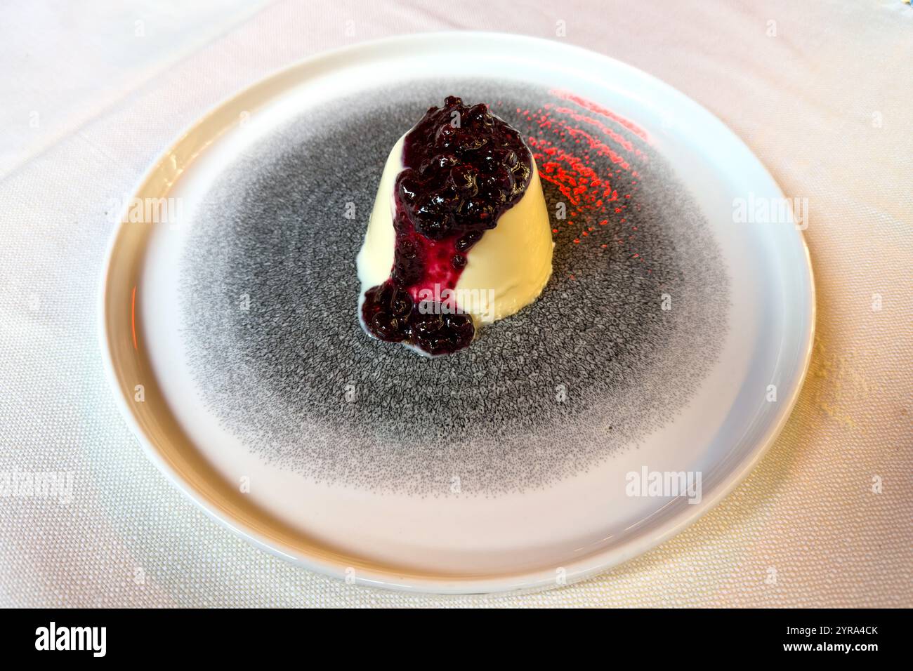 A traditional panna cotta dessert with a mixed berry sauce in a ...