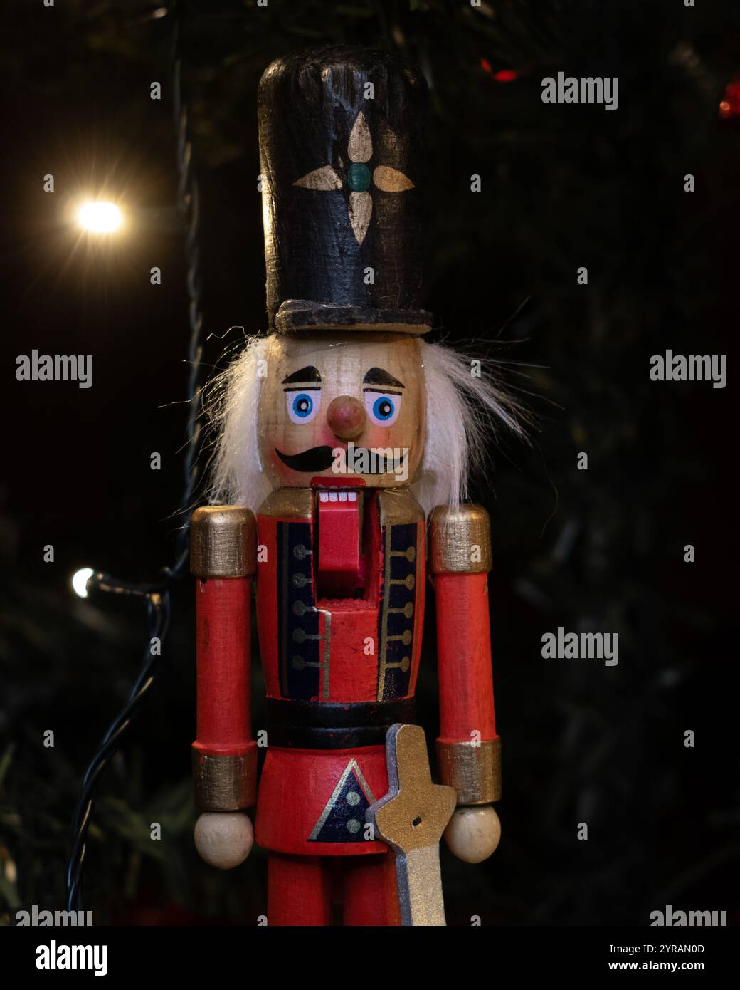 Red wooden nutcracker toy with lights on a black background with copy ...