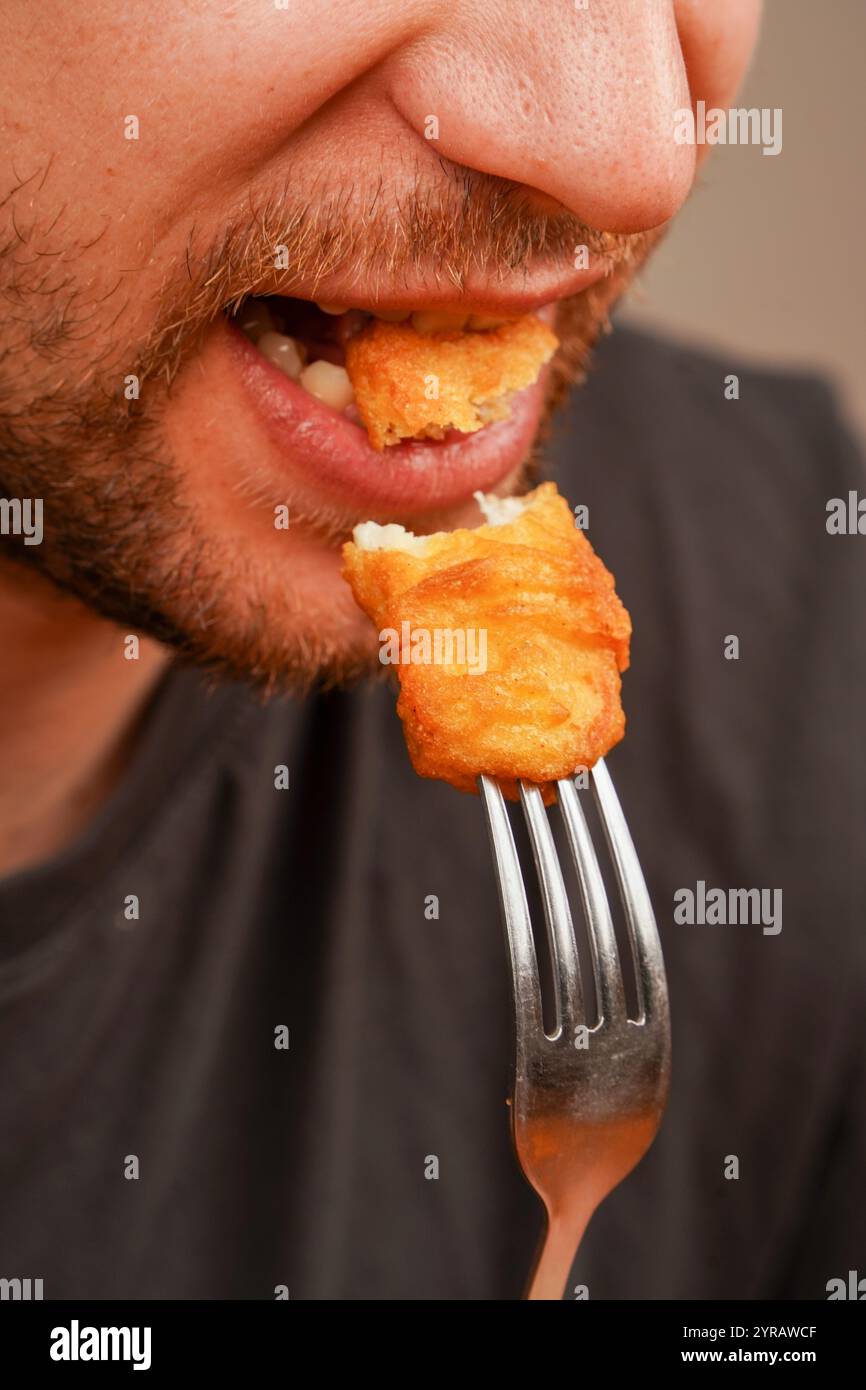 A close-up of a man eating a golden crispy nuggets highlights the ...