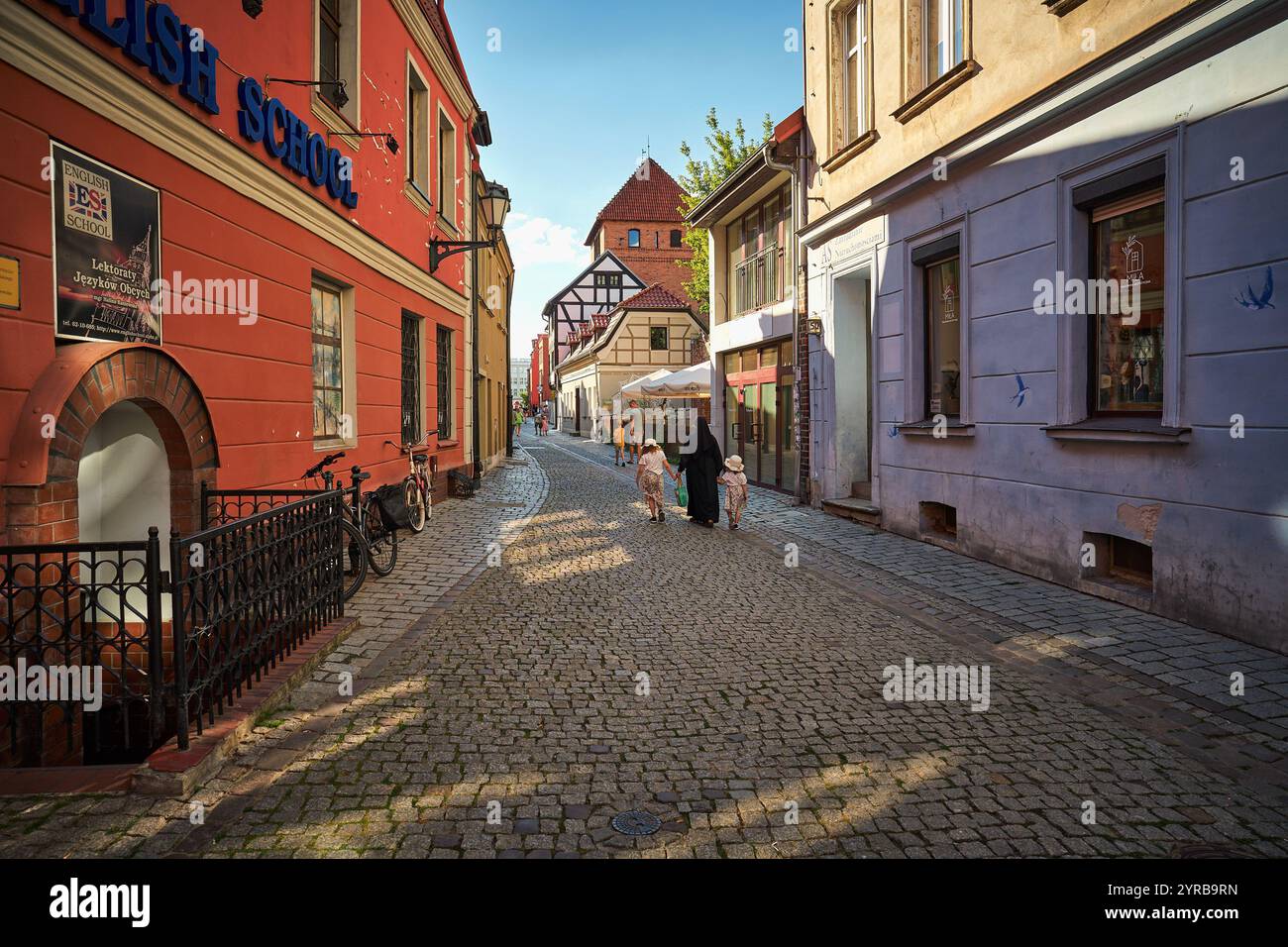 A charming cobblestone street in Torun, featuring colorful buildings ...