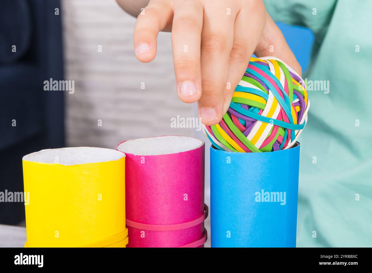 Preschooler hands with ball of colorful rubber bands or erasers ...