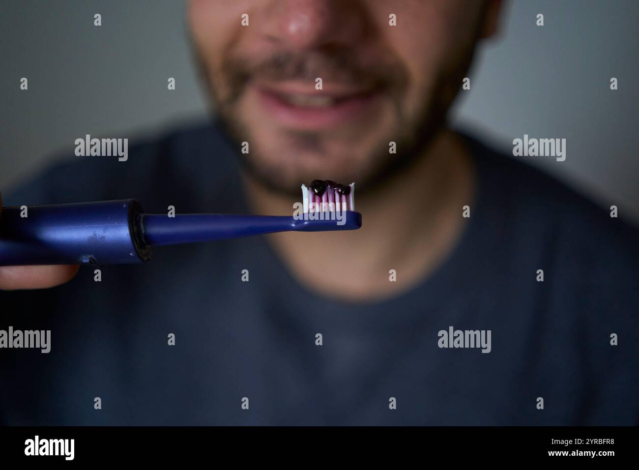 30-year-old man brushes his teeth with purple toothpaste using an ...