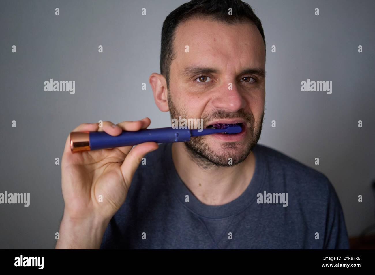 30-year-old man brushes his teeth with purple toothpaste using an ...
