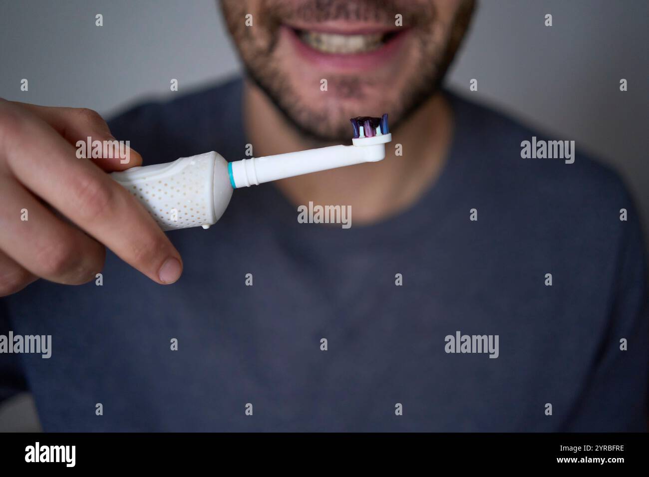 30-year-old man brushes his teeth with purple toothpaste using an ...