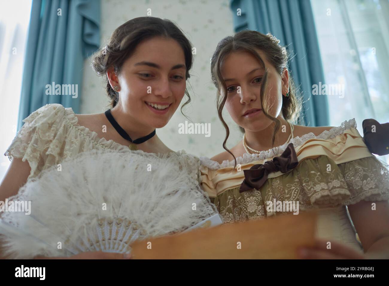 Low angle view of two romantic young ladies reading letter together and ...