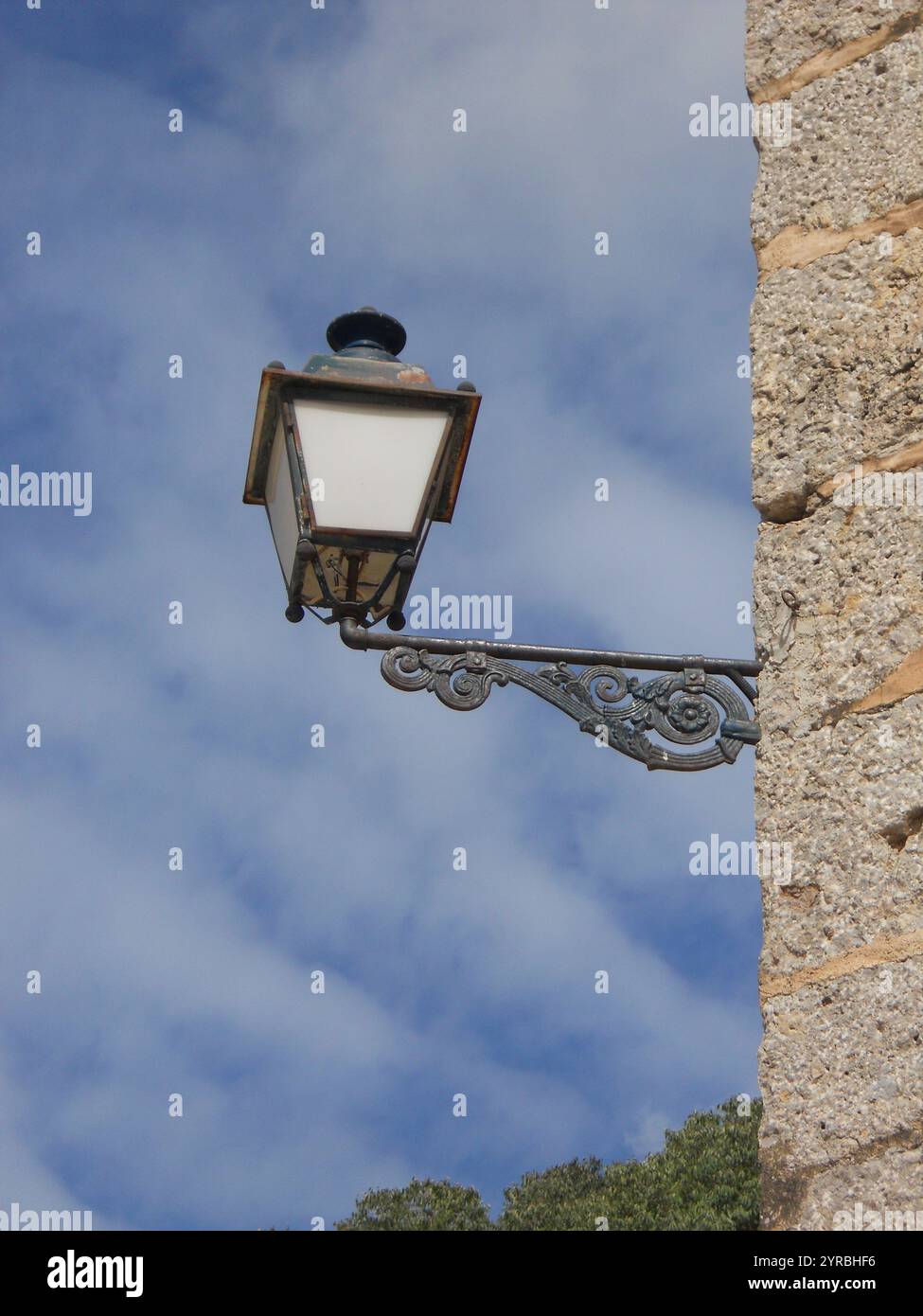 A vintage street lamp is mounted on a stone building, contrasting ...