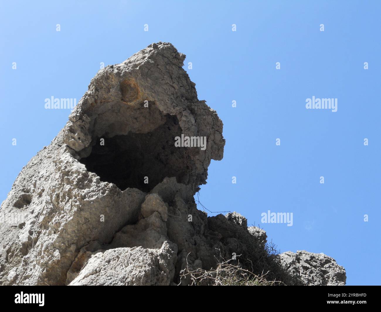 A striking rock formation with a hollowed center towers against a ...