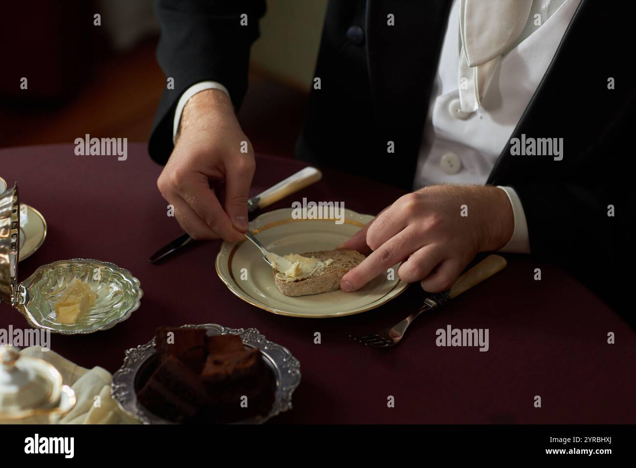 Top view closeup of young gentleman putting butter on slice of bread at ...
