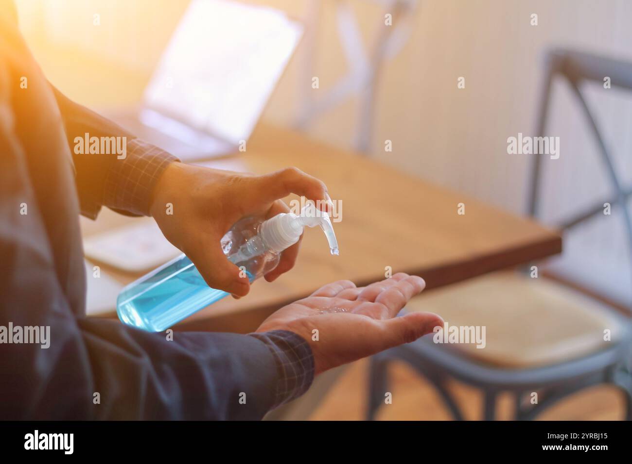 A young businessman uses alcohol gel prepared in the office to wash his hands after attending a ...