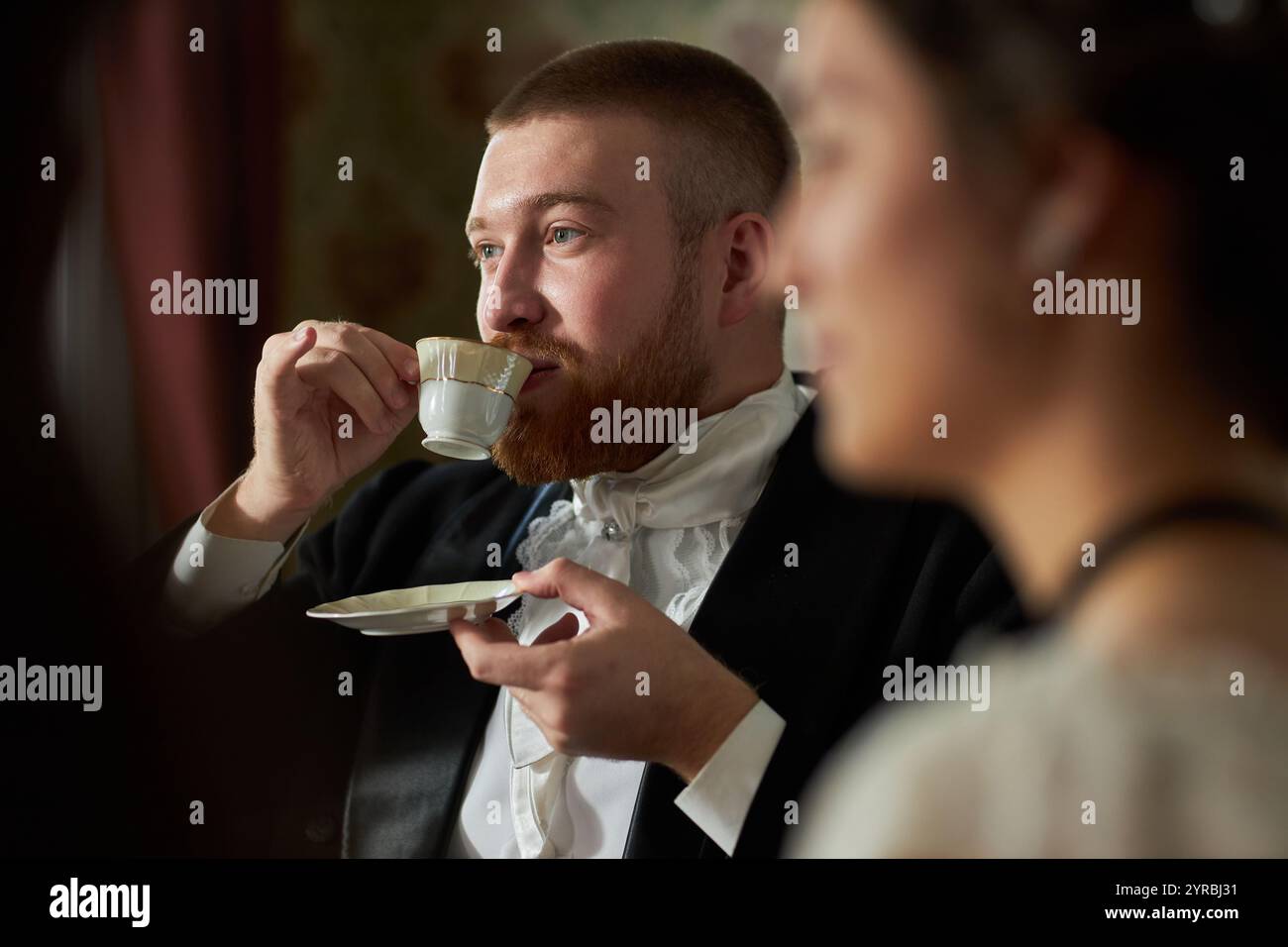 Side view portrait of young gentleman sipping tea delicately from ...