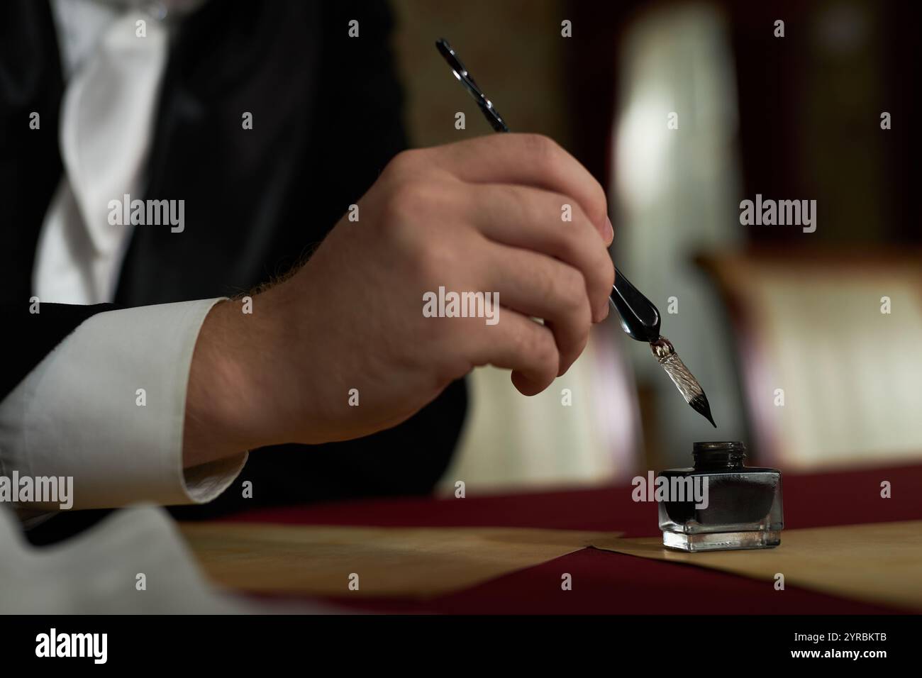 Side view close up of male hand dipping fountain pen in ink while ...