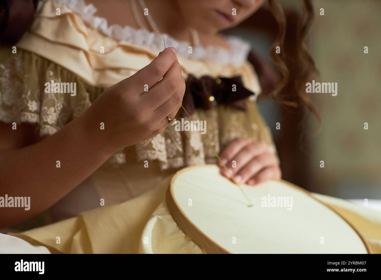 Side view detail shot of young lady guiding thread through fabric doing ...