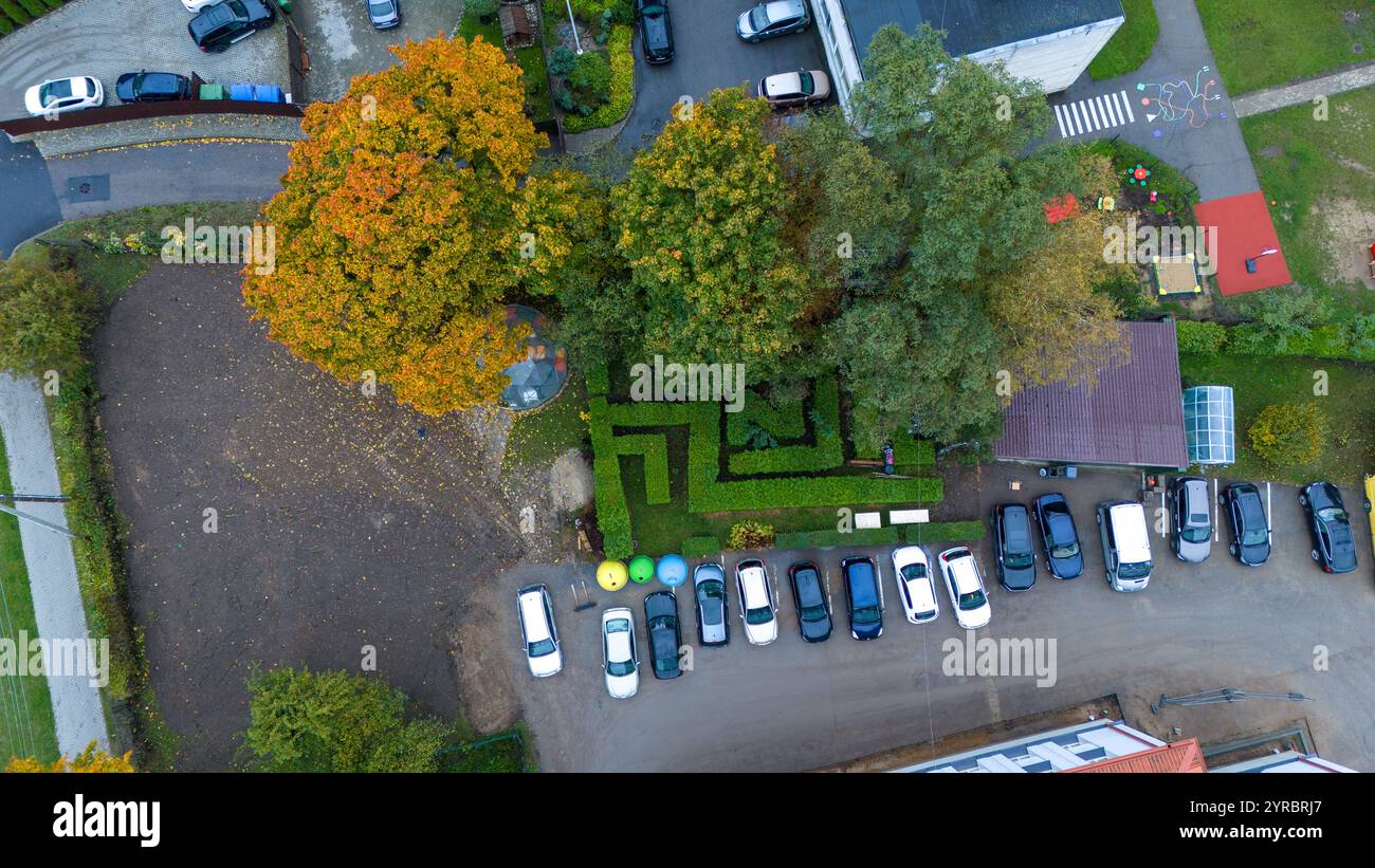 Aerial view of a parking lot with cars and a garden with trees and ...