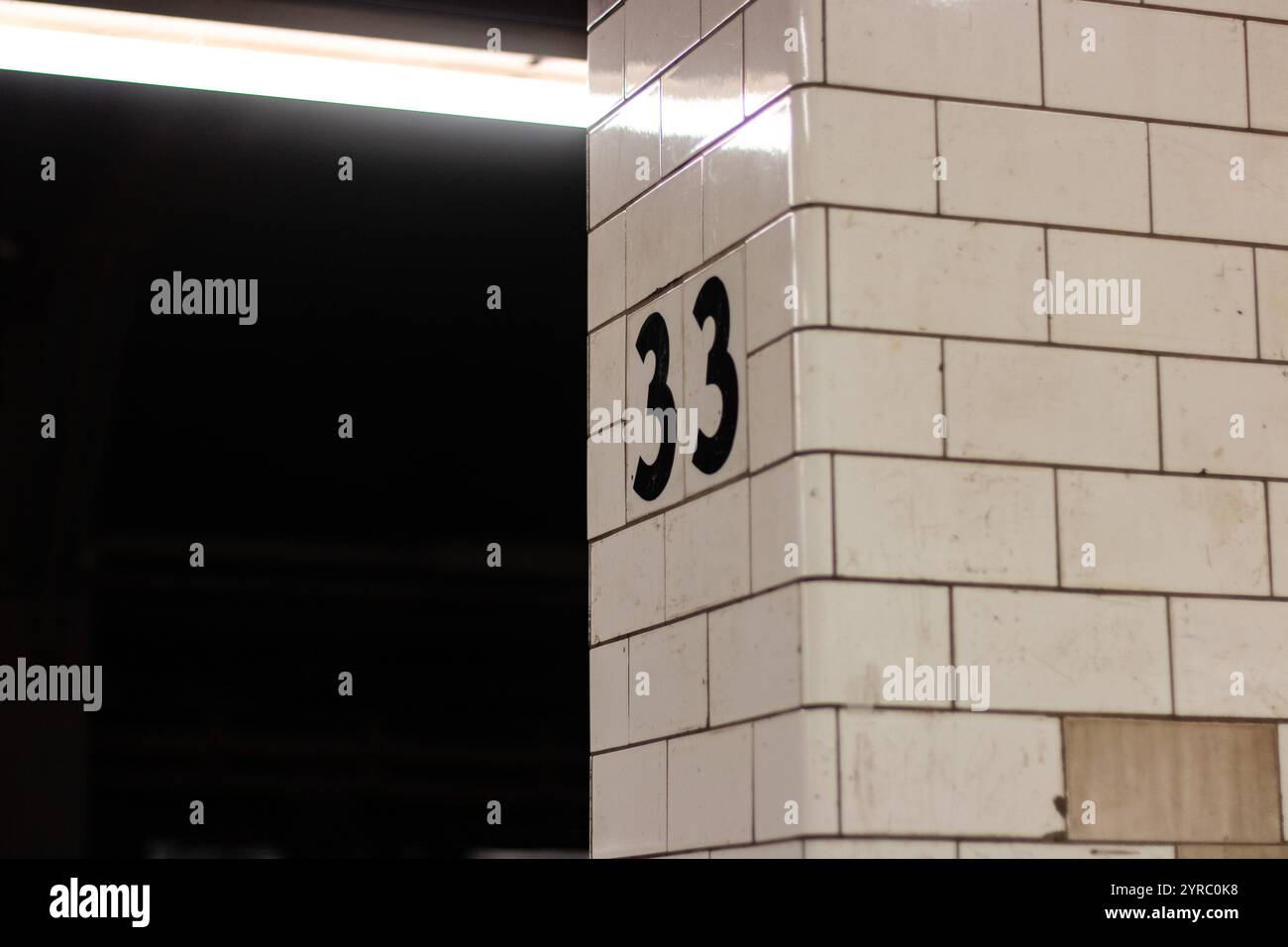 A corner pillar with the number 33 on white subway tiles at an NYC ...