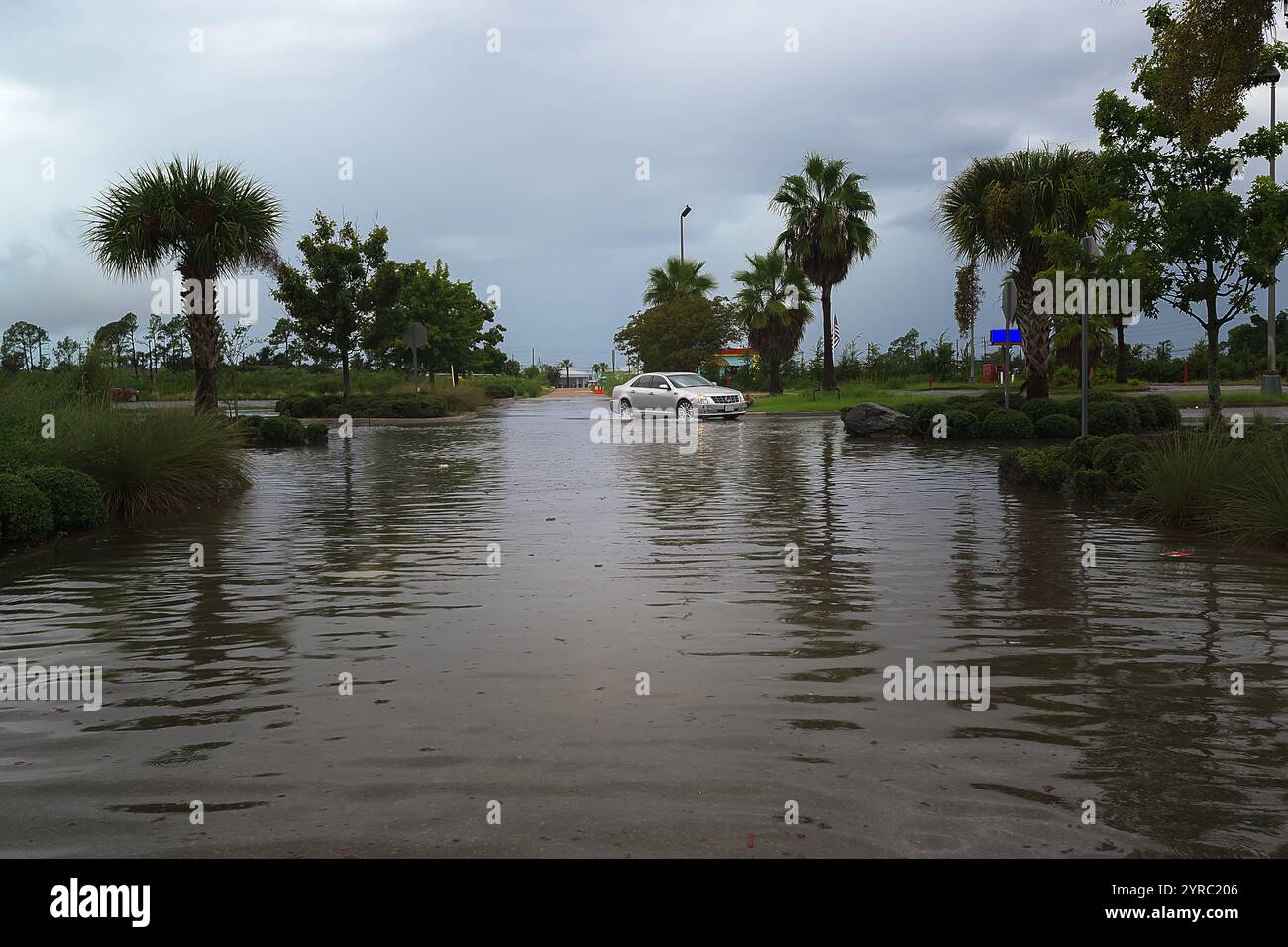 vehicle driving in parking lot submerged under heavy rain, with water pooling creating stormy ...