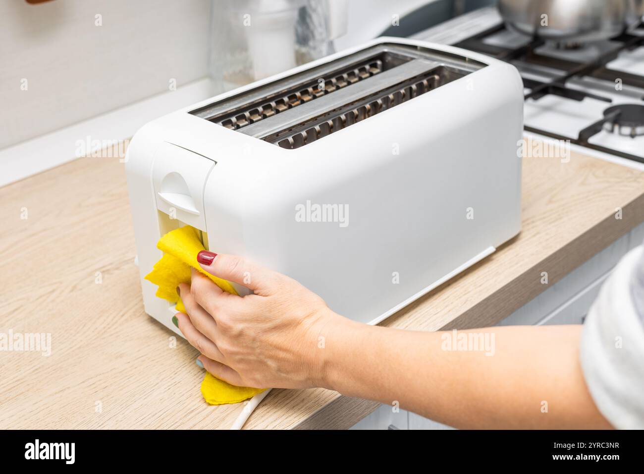 housewife in the kitchen wiping a toaster with a rag. Caring for your ...
